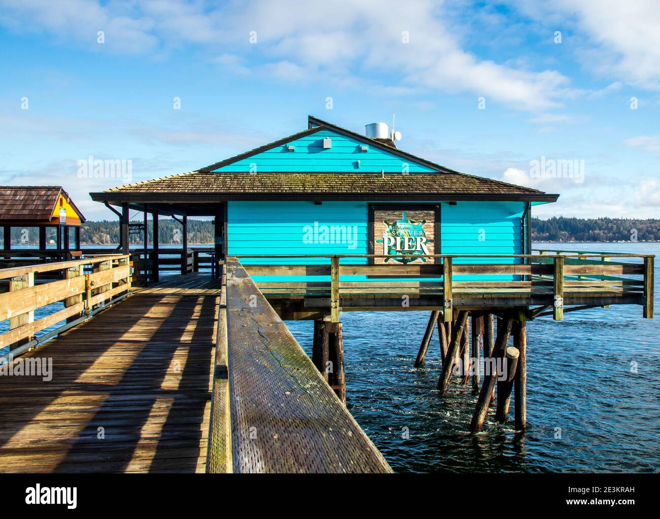 Turquoise building on pier in Campbell River, BC. Wooden walkway on a ...