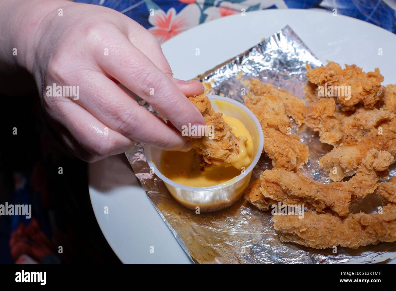 Woman dipping a chicken tender in honey mustard sauce Stock Photo - Alamy