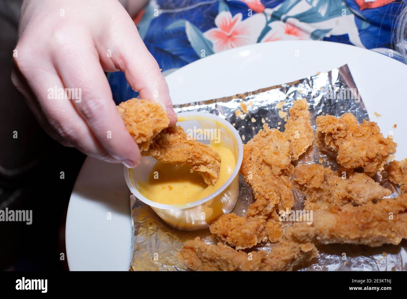 Woman dipping a chicken tender in honey mustard sauce Stock Photo - Alamy
