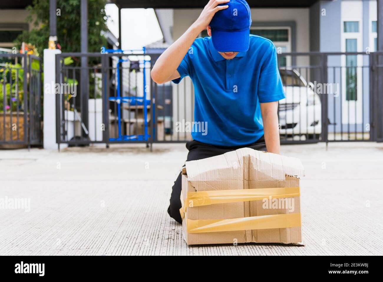Asian young delivery man in blue uniform he emotional falling courier ...