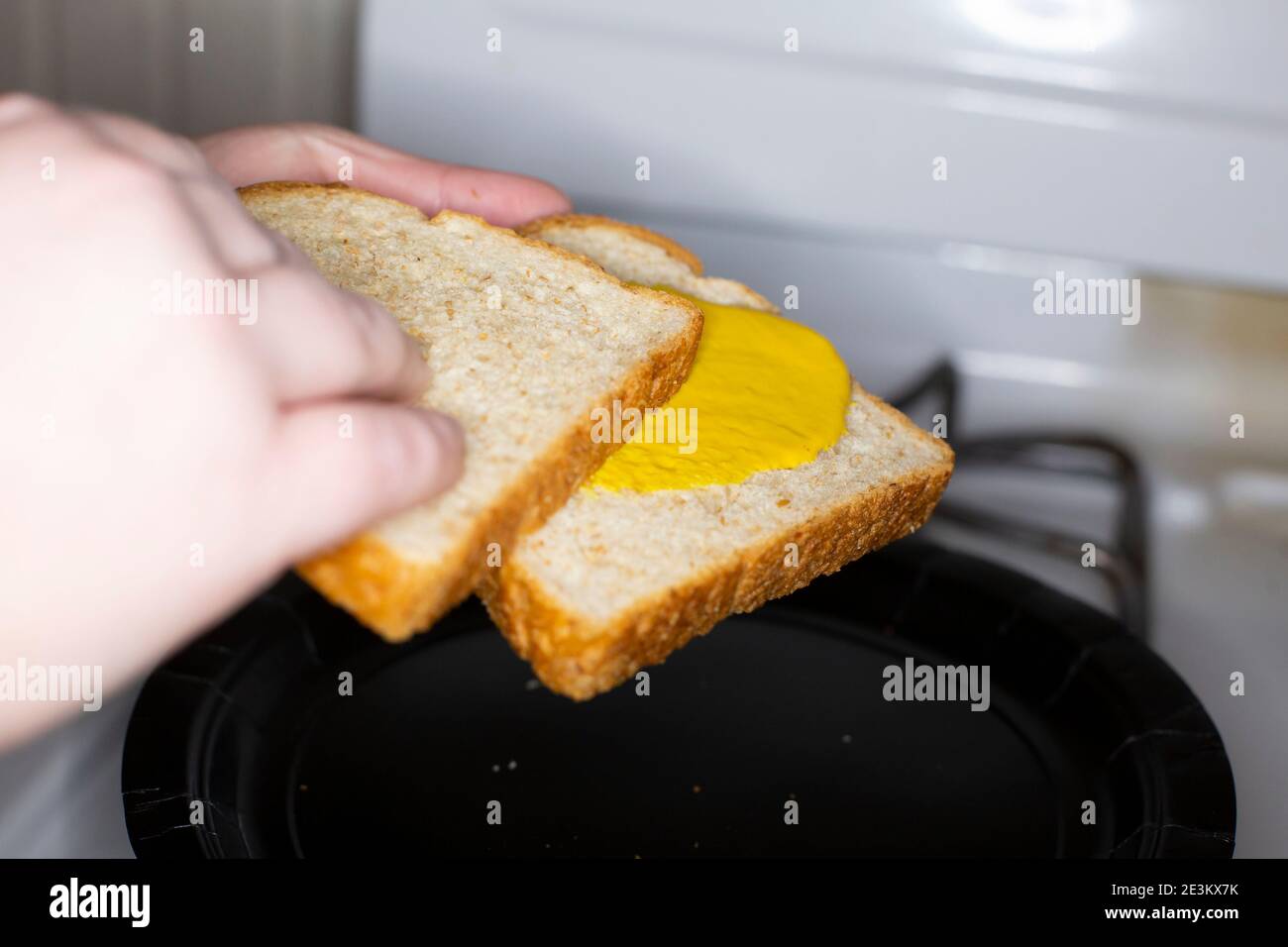 Rubbing mustard on two slices of bread for a sandwich Stock Photo - Alamy