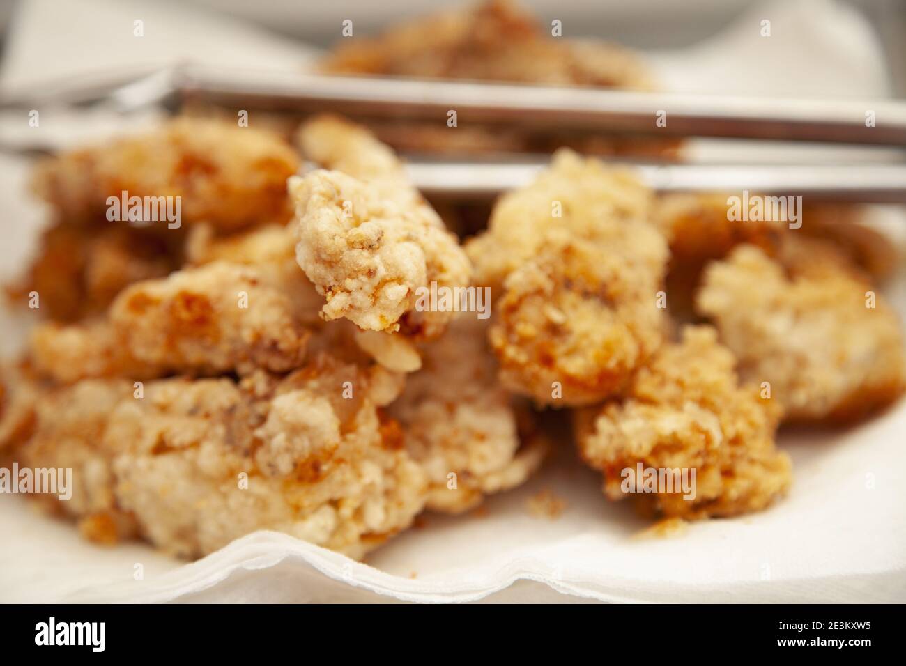 Homemade fried chicken strips and cooking tongs on a paper towel Stock ...