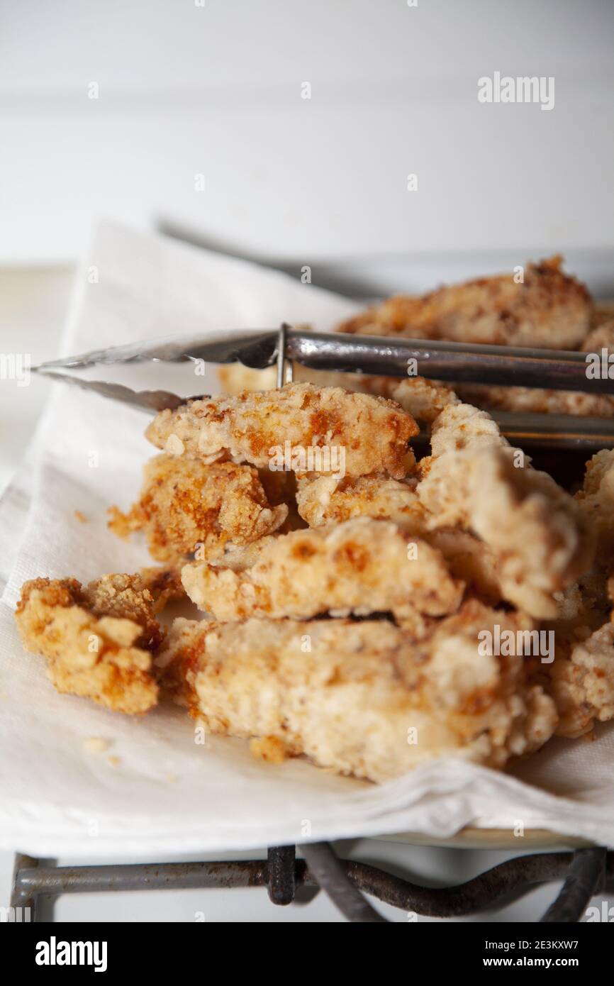 Homemade fried chicken strips and cooking tongs on a paper towel Stock ...