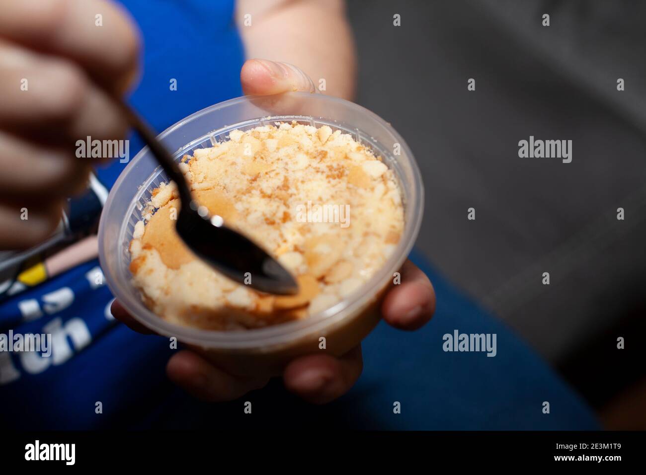 Person eating from a small carryout container of banana pudding Stock ...