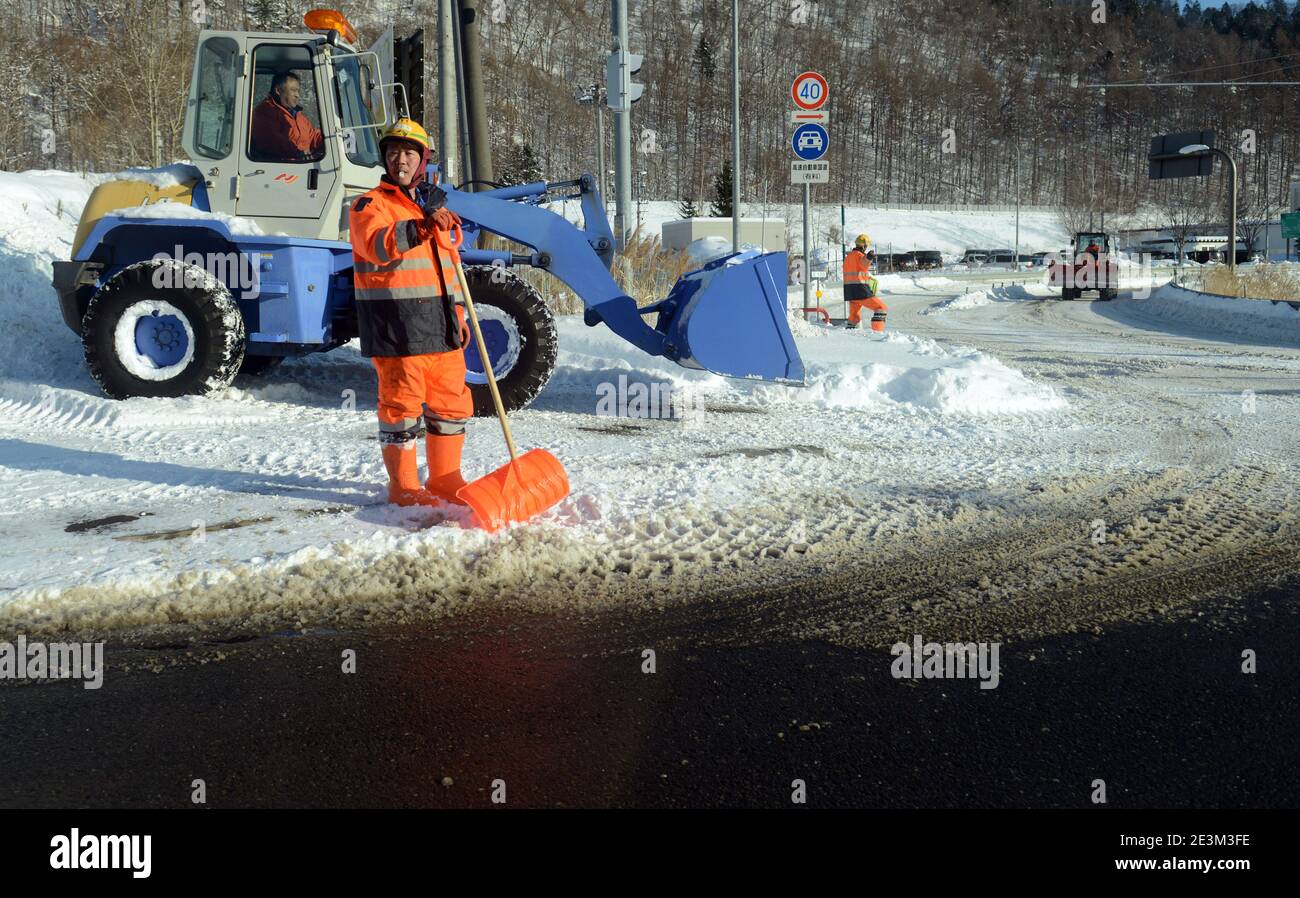 A Japanese road construction worker clearing ice from the road in rural ...