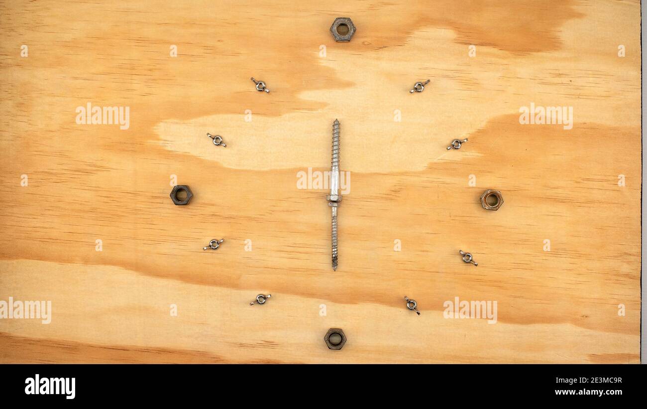 Creative concept of a clock made of bolts, wing nuts and screws. Timber ...
