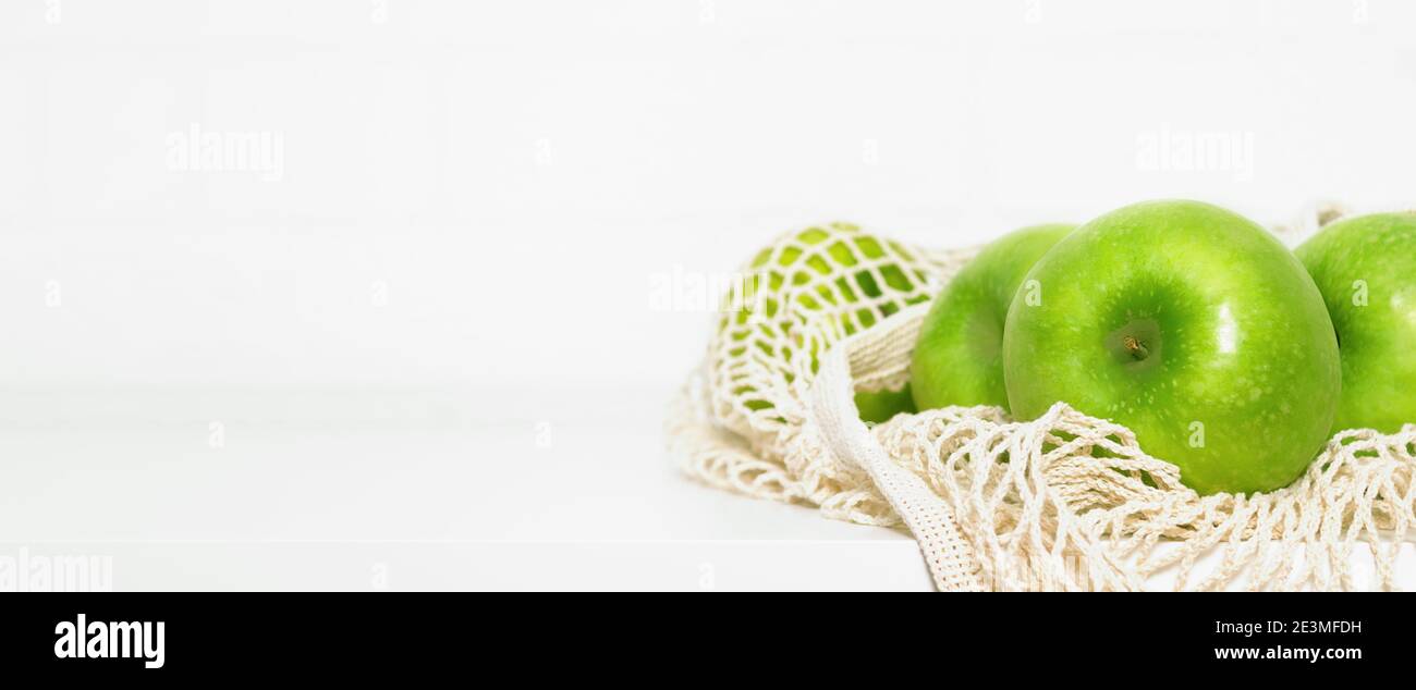 Green apples in eco mesh bag on white kitchen table. Market shopping ...