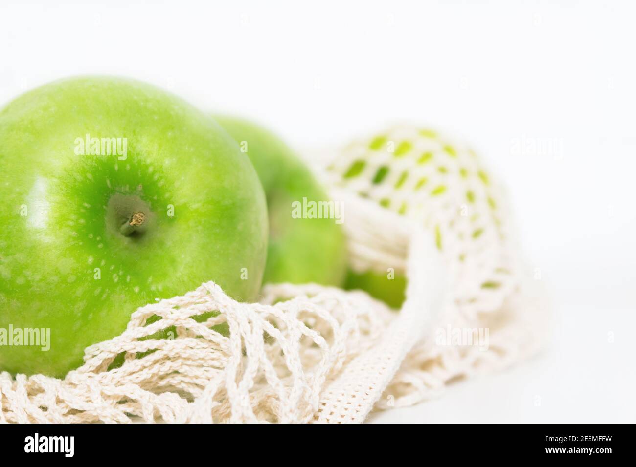 Green apples in eco mesh bag on white kitchen table. Market shopping ...