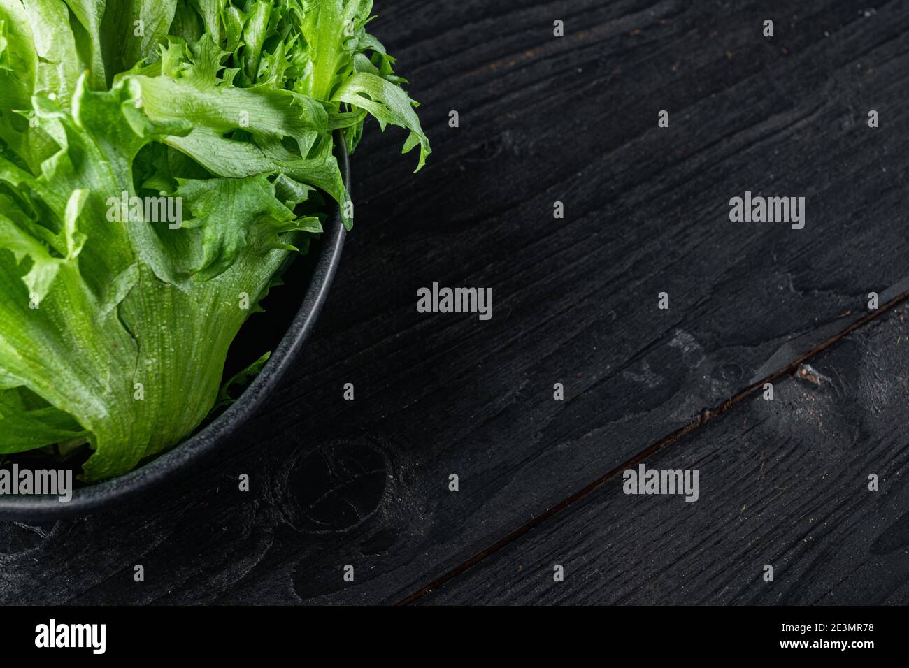 Frillis lettuce leaves, on black wooden table background with copy ...
