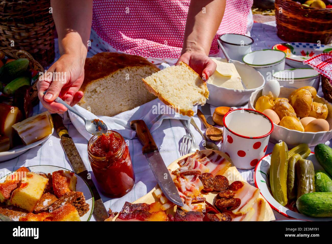Traditional meal, woman smears jam on bread, breakfast in open at the ...