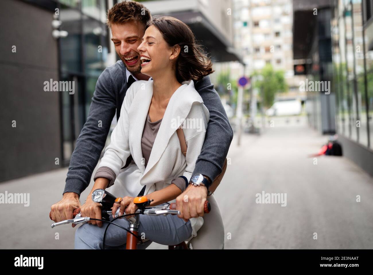 Portrait of happy young couple riding a bike and having fun together ...