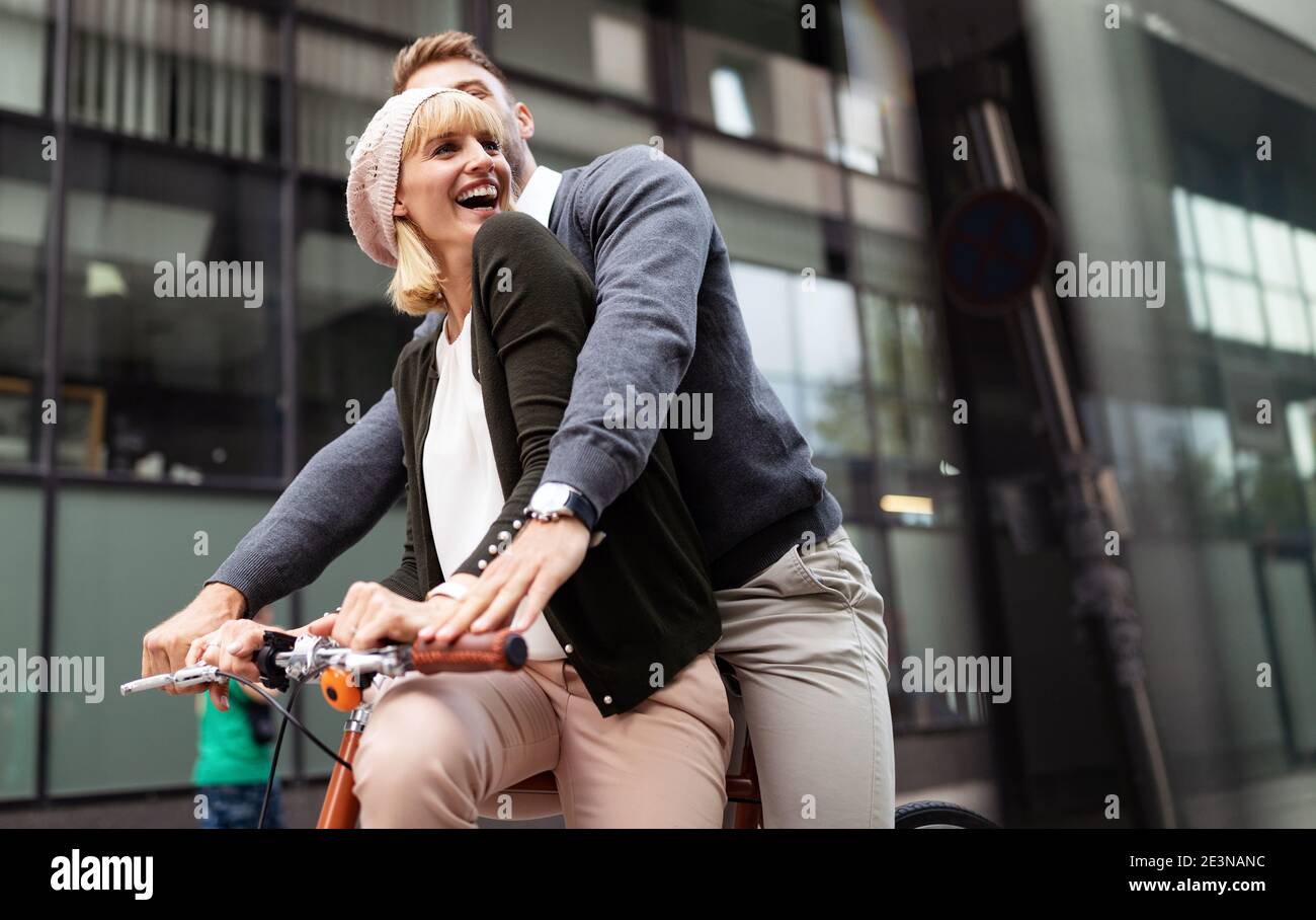 Portrait of happy young couple riding a bike and having fun together ...