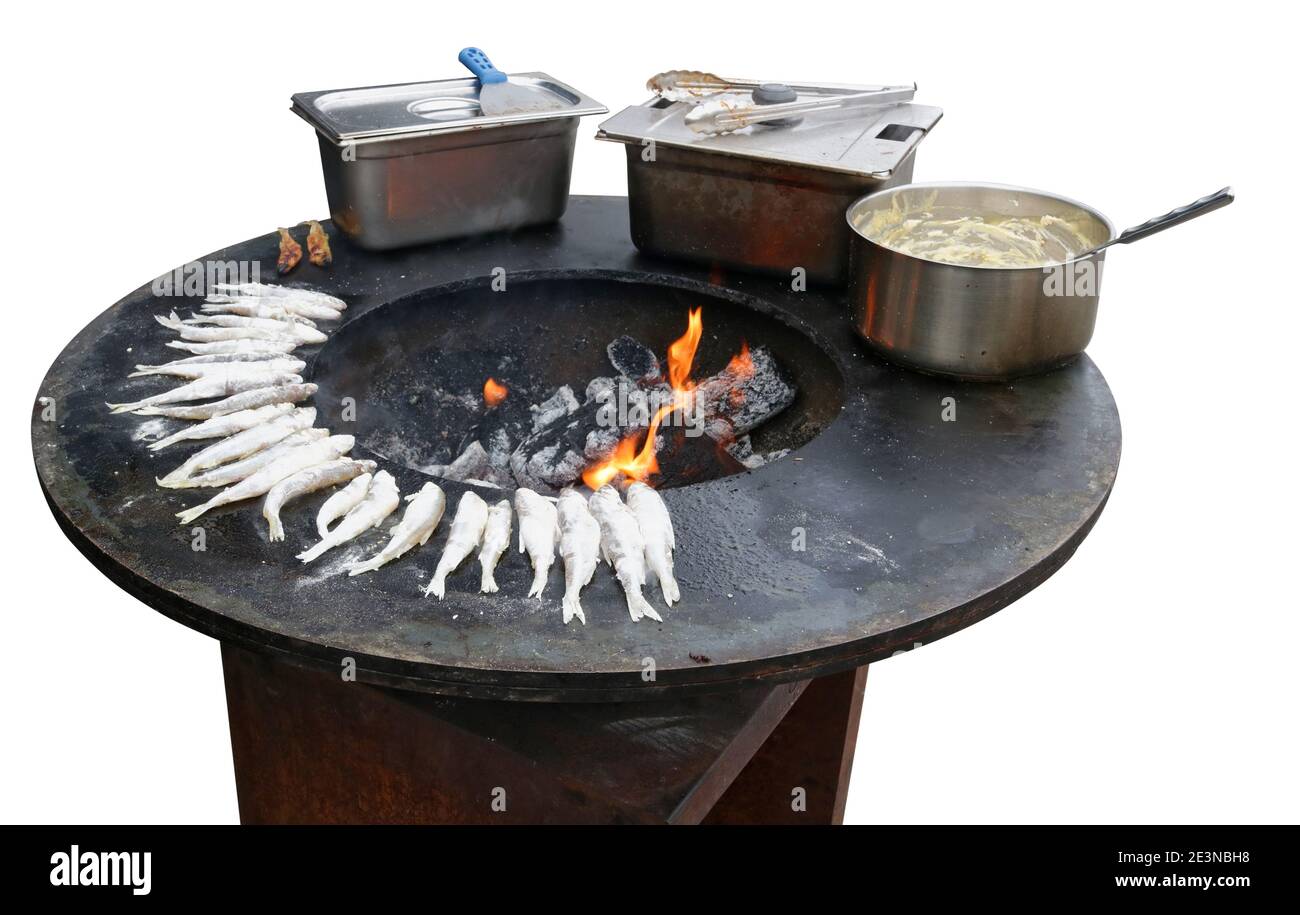 Round street cast-iron brazier with coals for frying fish. Isolated on ...