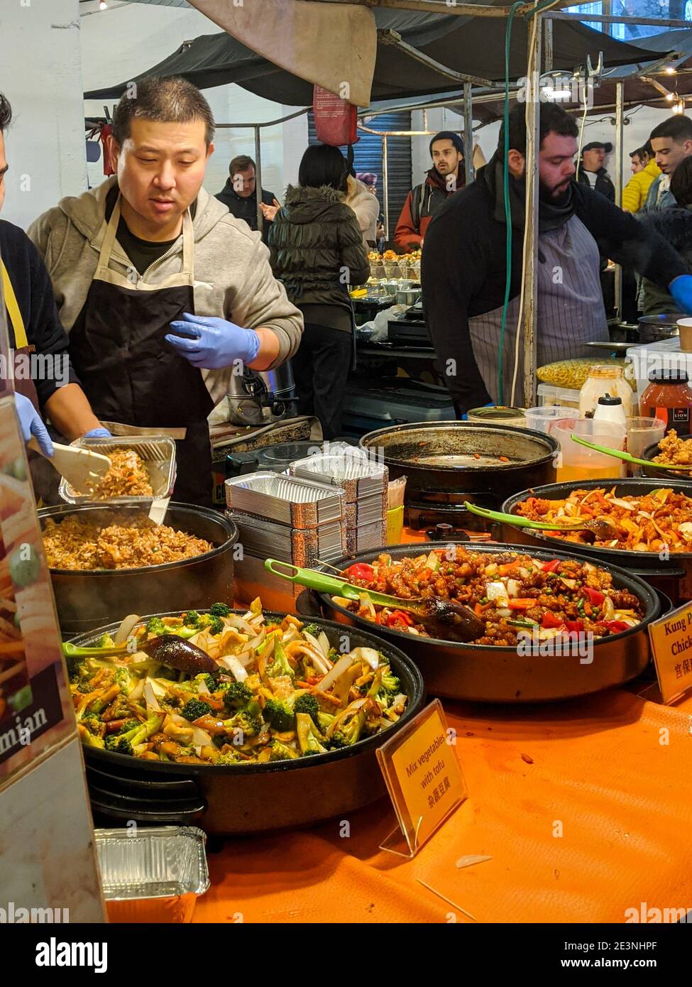 Asian man oversees preparation of assorted Asian food at street food ...