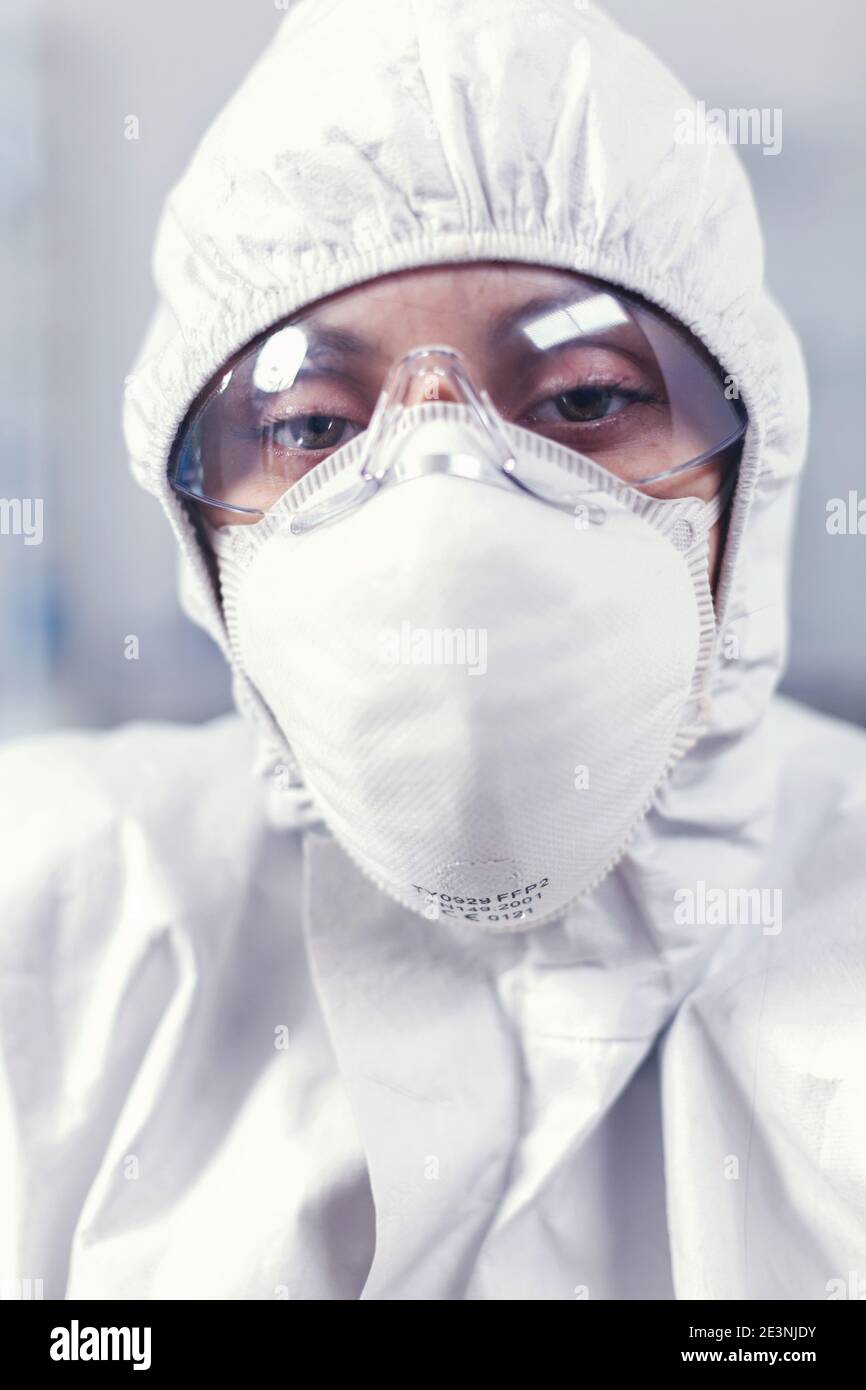 Microbiologist sitting in laboratory wearing ppe looking at camera in ...
