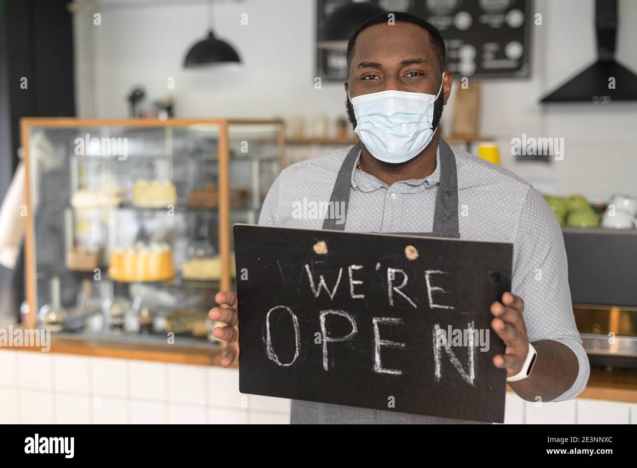 An African waiter in a medical mask with open sign Stock Photo - Alamy