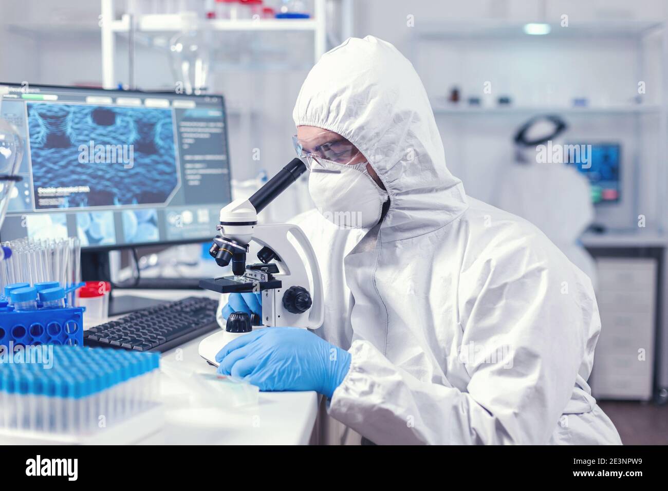 Doctor researching and evaluating virus using microscope in laboratory ...