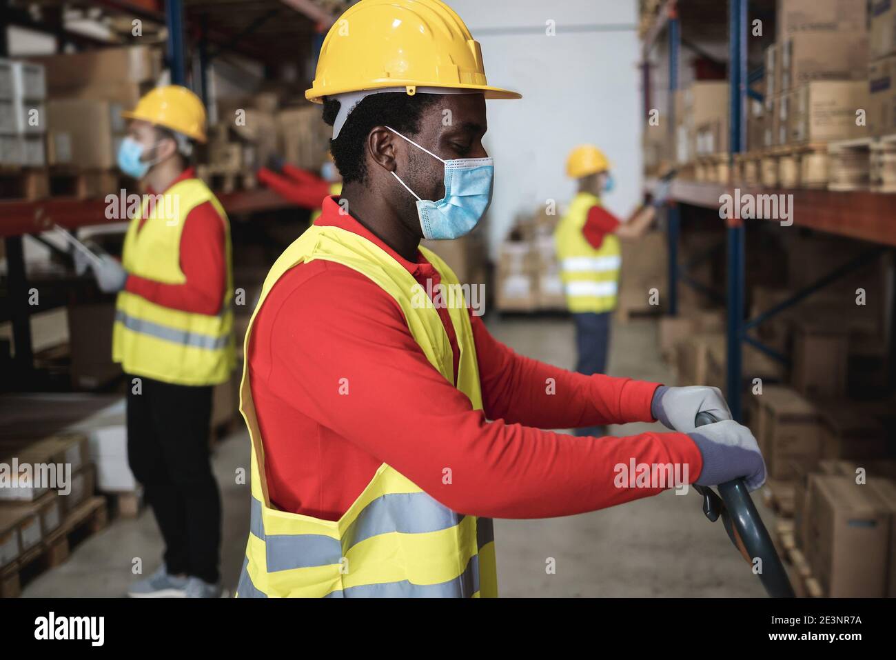 African warehouse worker loading delivery boxes while wearing safety ...