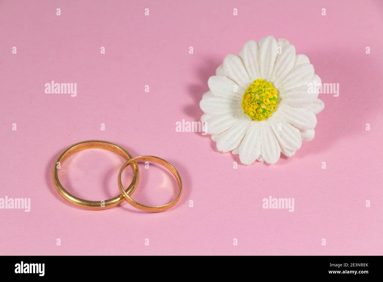 Two wedding rings and daisy Stock Photo - Alamy