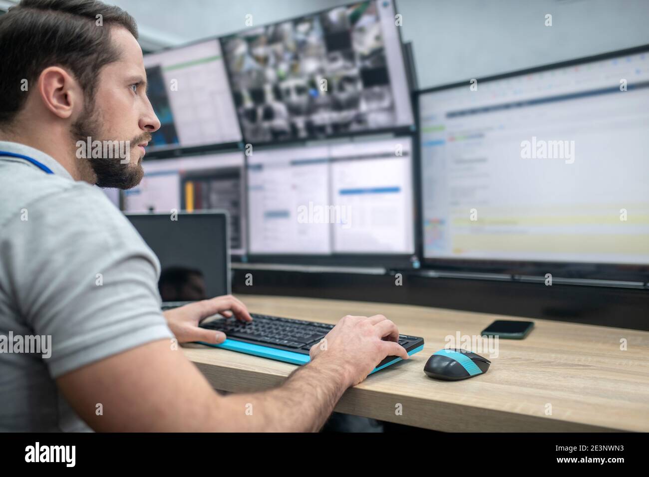 Attentive man with keyboard in front of computer screens Stock Photo ...