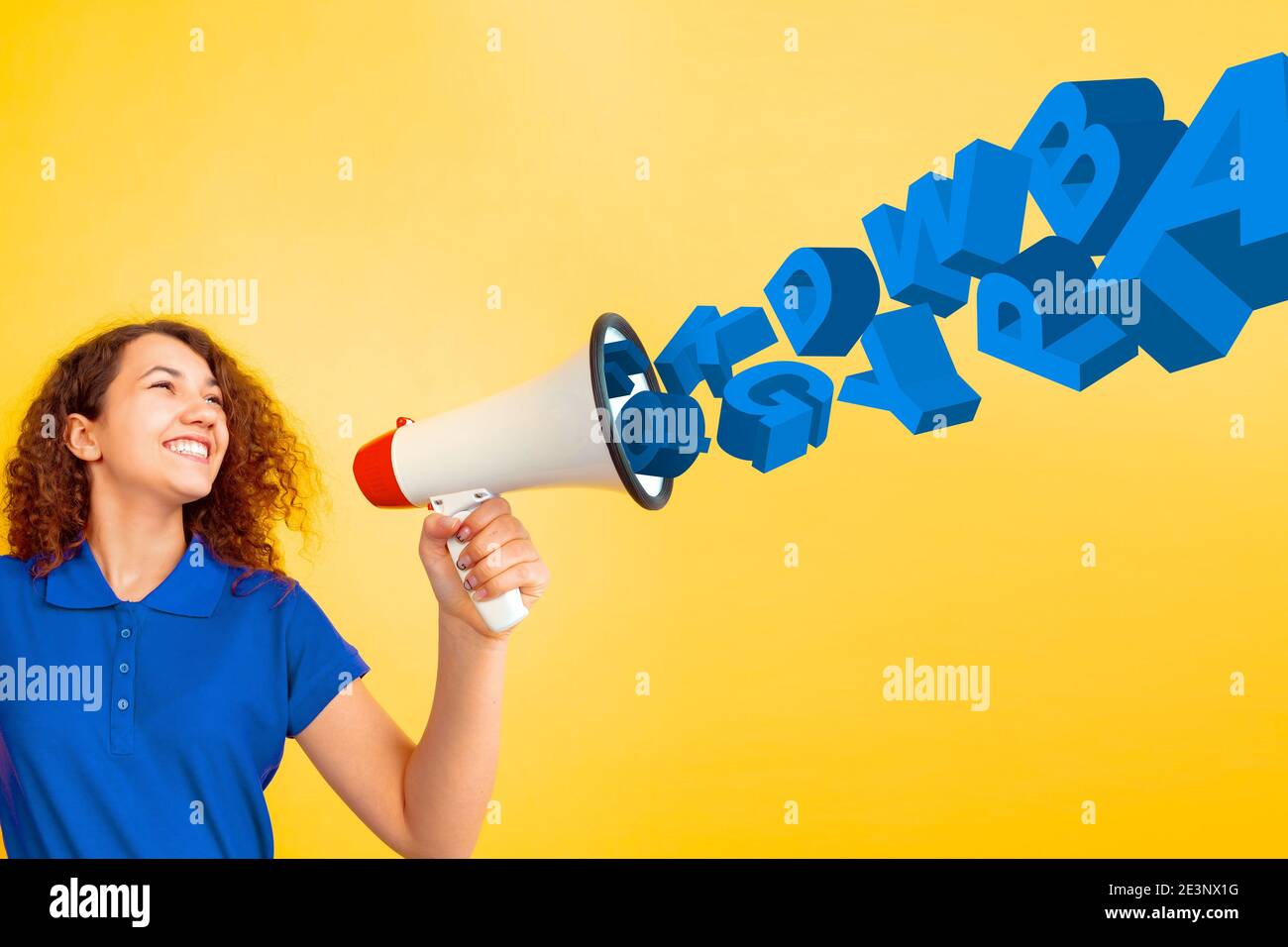 Caucasian girl shouting with megaphone, loudspeaker on yellow studio ...
