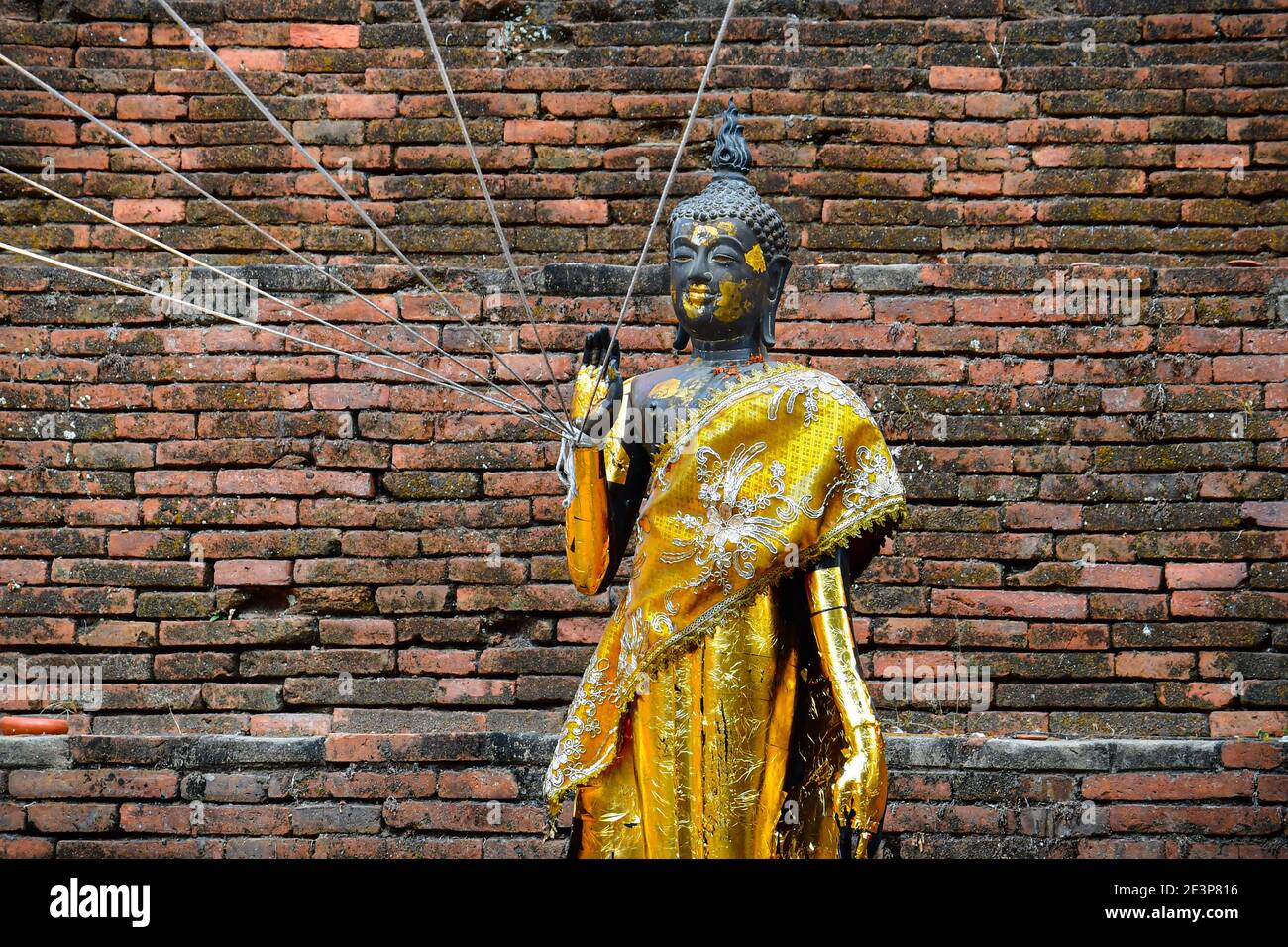 A Buddha statue wearing an ornate golden robe, with sacred threads ...