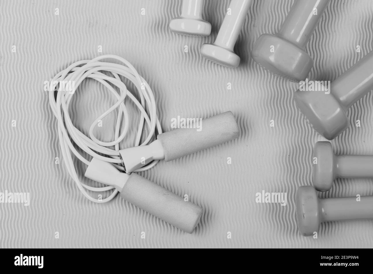 Barbells in pink, green and blue near jump rope. Shaping and fitness ...