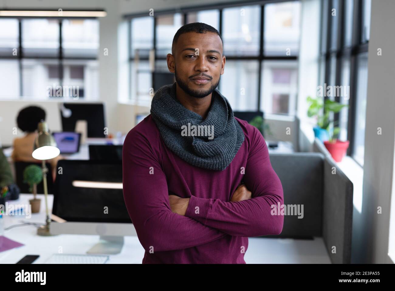 Portrait of mixed race businessman in creative office smiling with arms ...