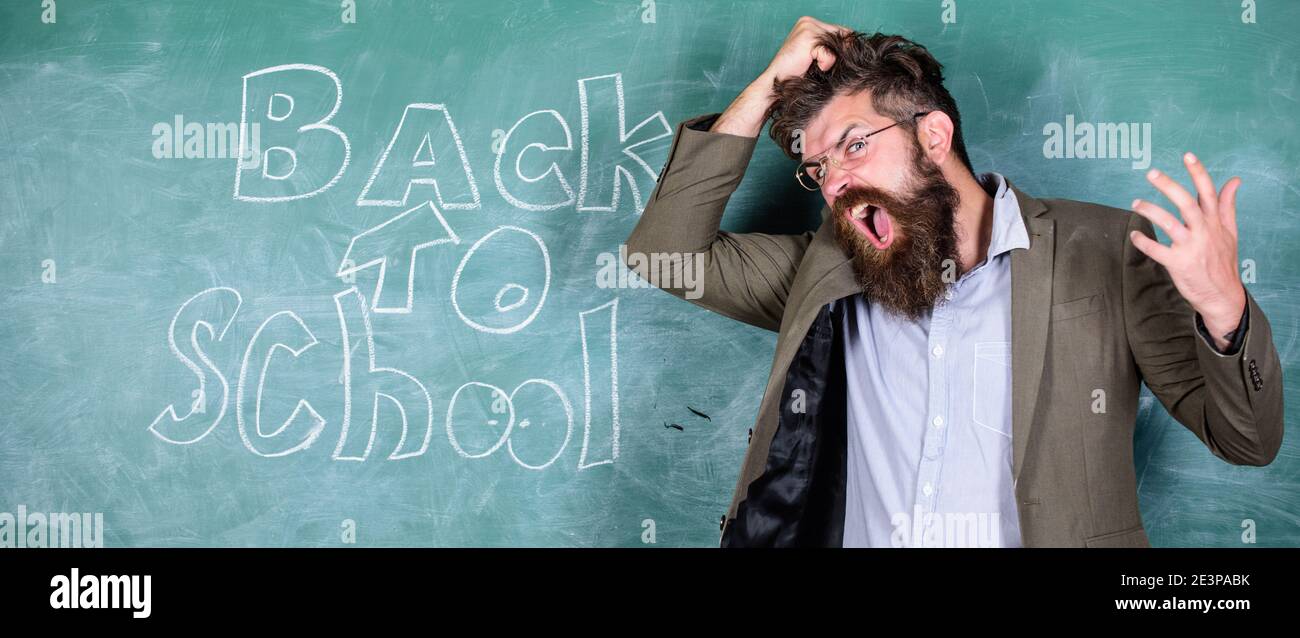 Teacher or educator stands near chalkboard with inscription back to ...