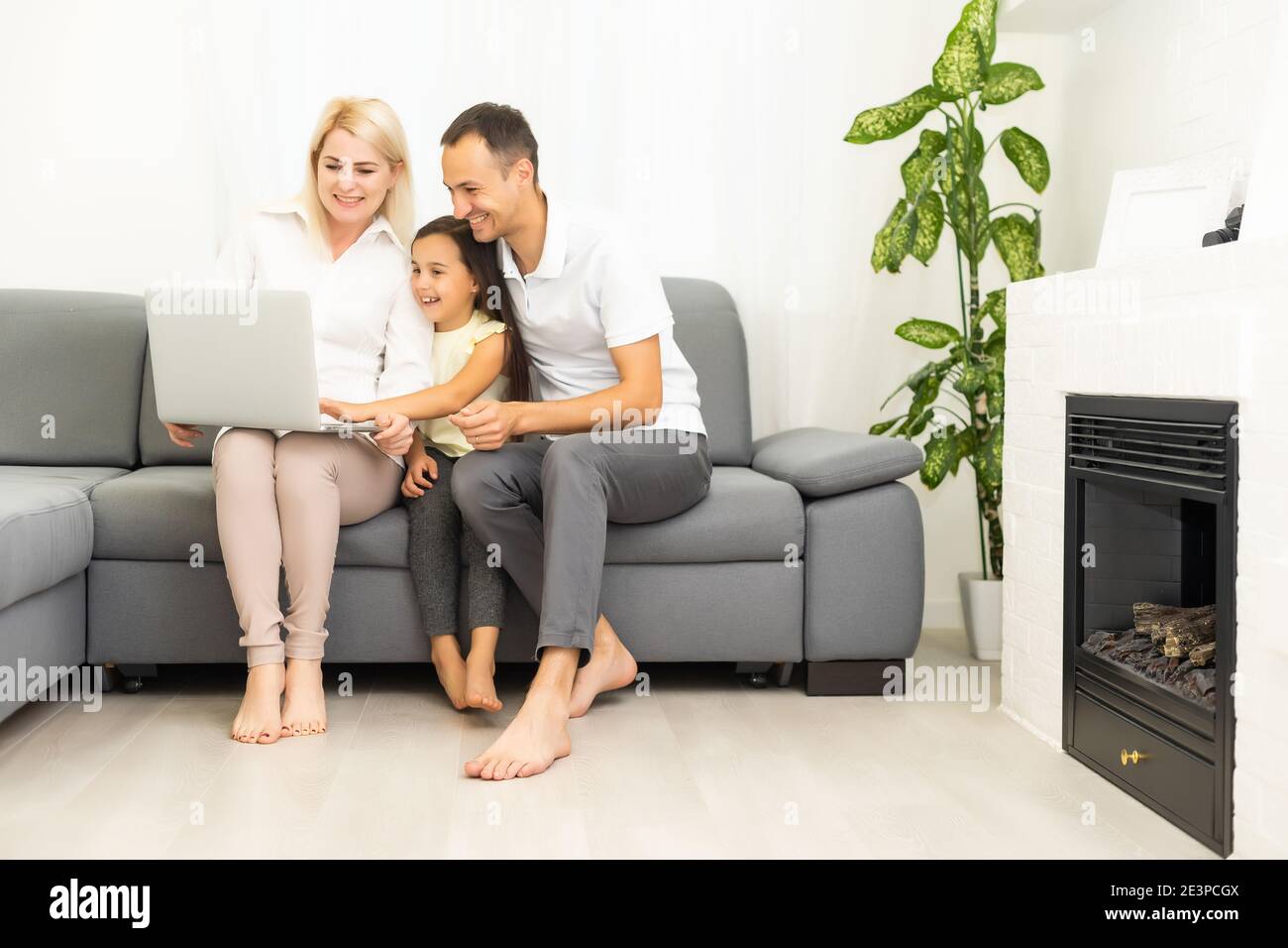 Happy family with kid girl having fun using laptop together sitting on ...