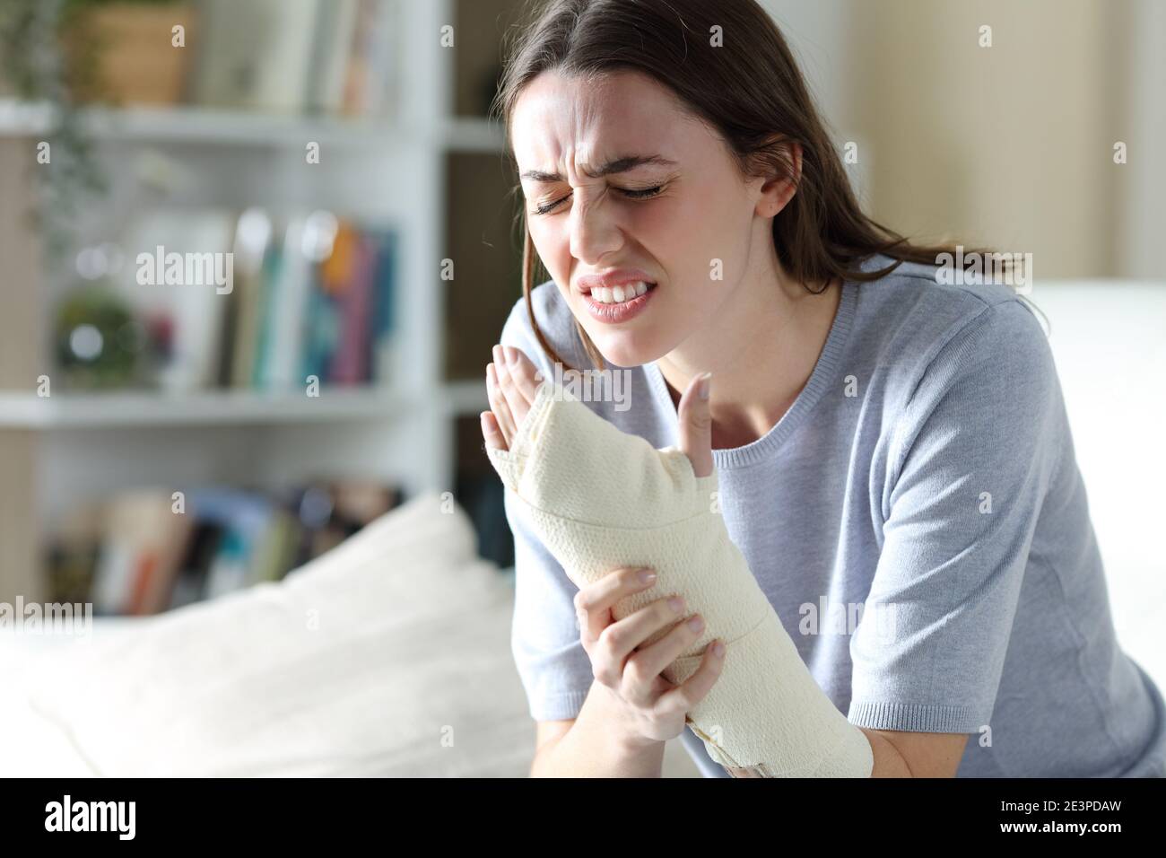 Woman with injured painful arm complaining sitting on a couch in the ...