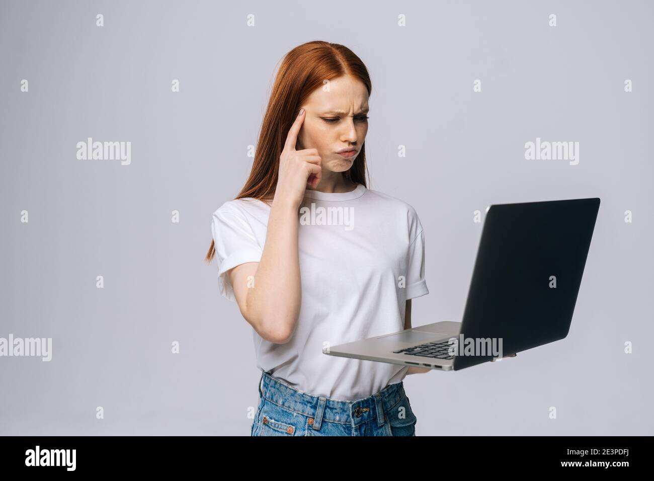 Thoughtful young woman student using laptop computer and looking at ...