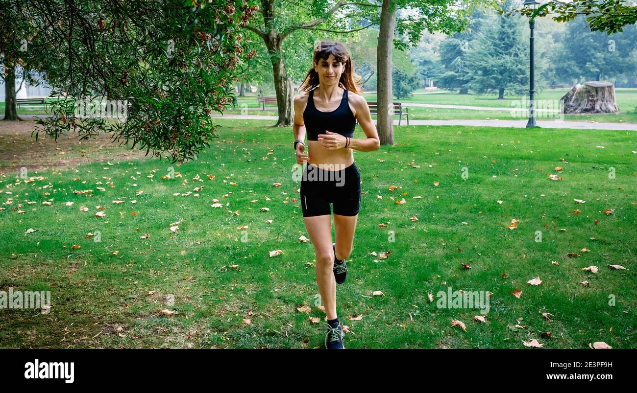 Female athlete running through a park Stock Photo - Alamy