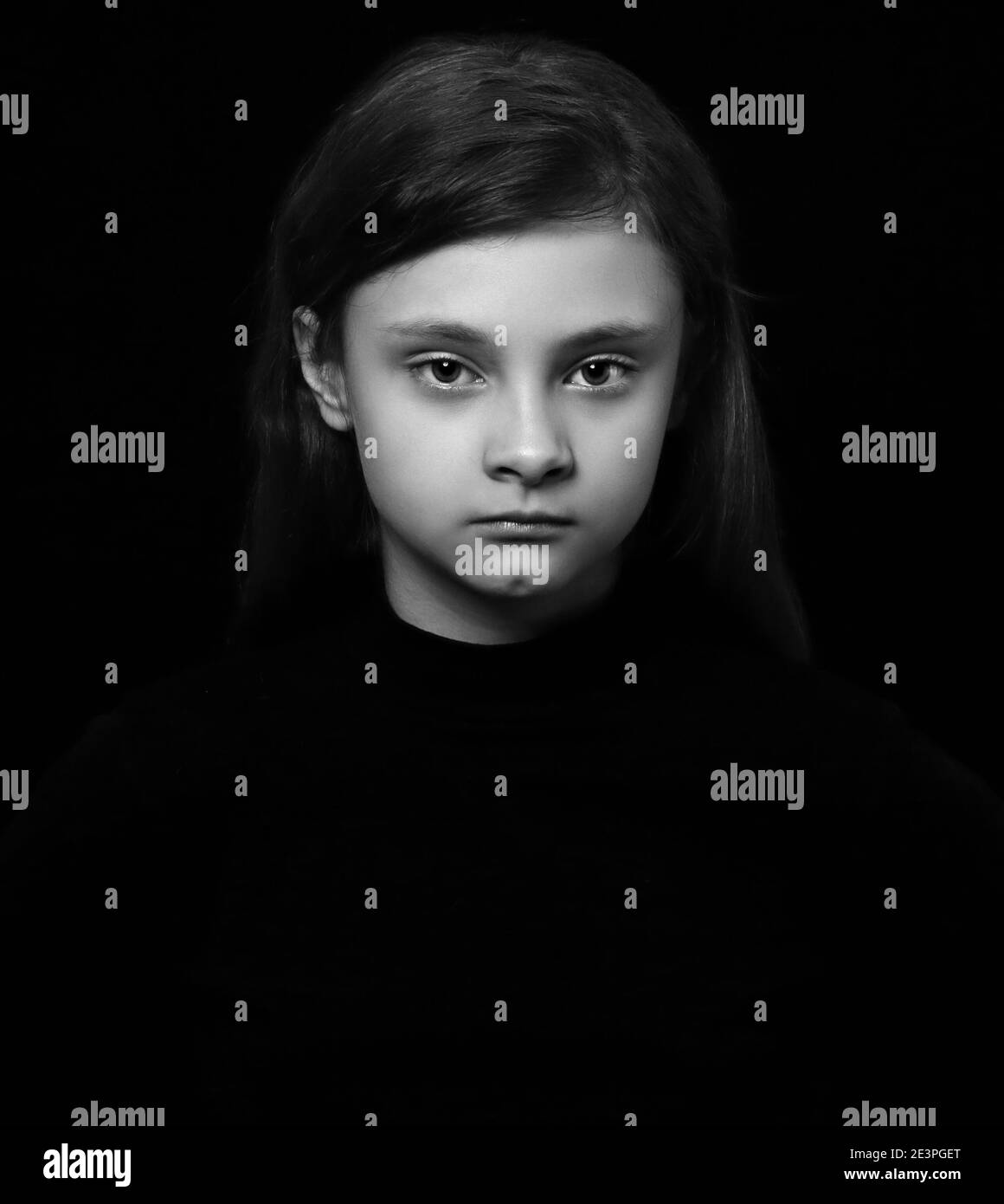 Unhappy serious kid girl with angry look on black background with empty ...