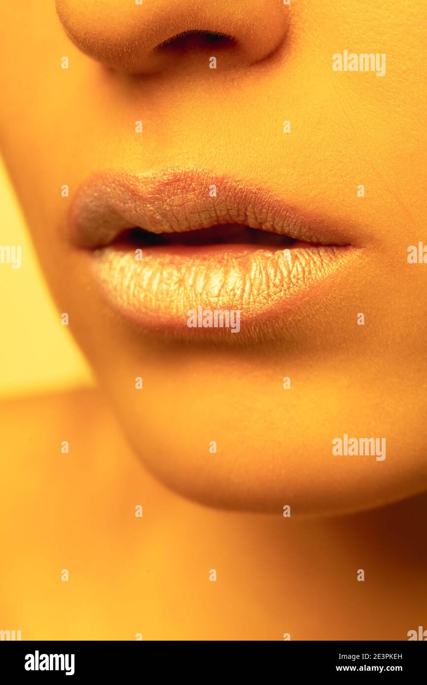 Lips. Beautiful east woman close up portrait in golden colored neon ...