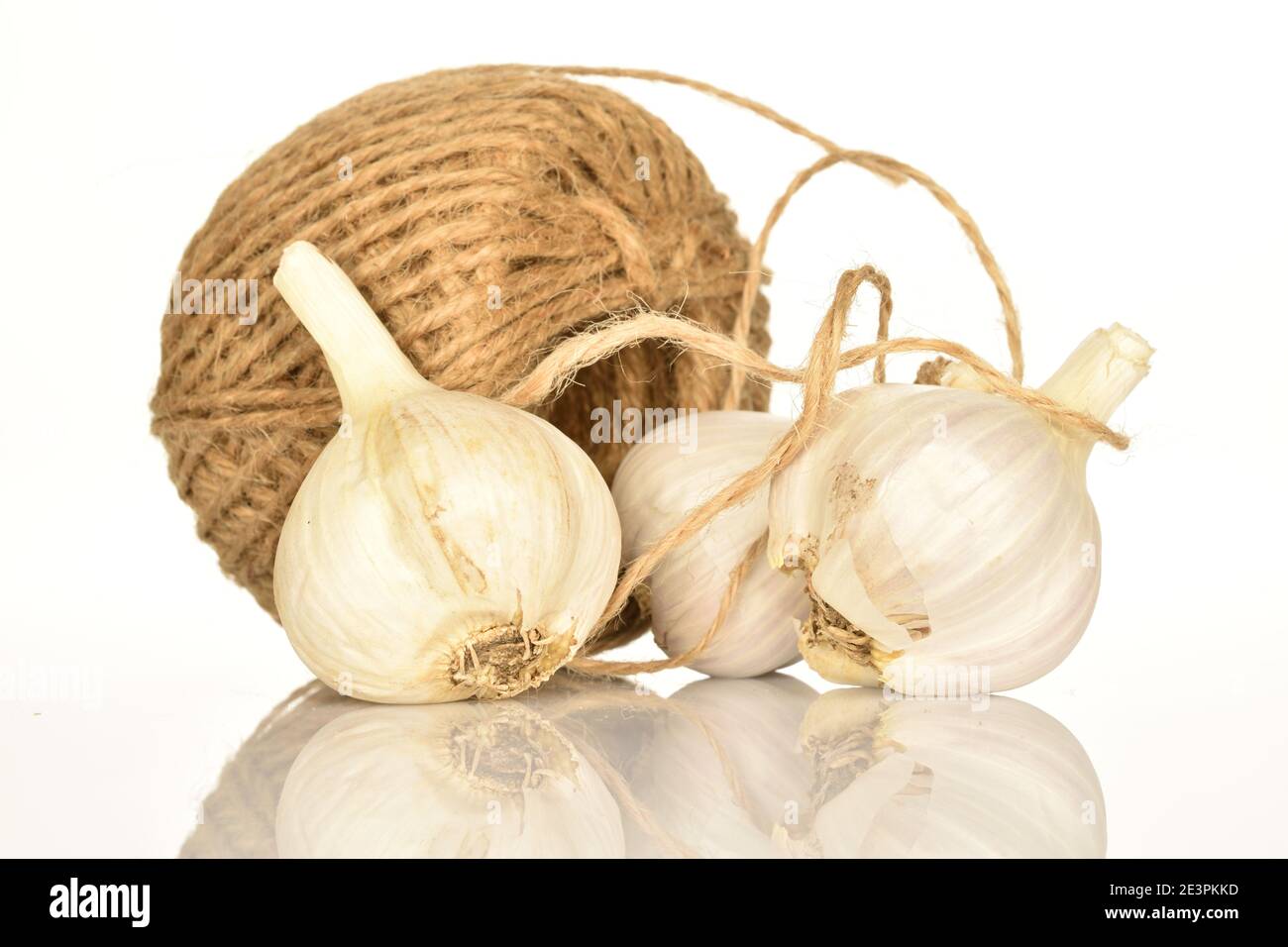 Three whole organic fragrant heads of garlic lying next to a ball of ...