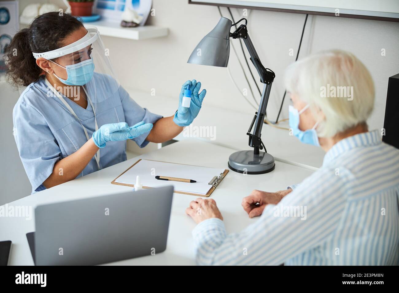 Female medical practitioner suggesting blue bottle of drops Stock Photo ...