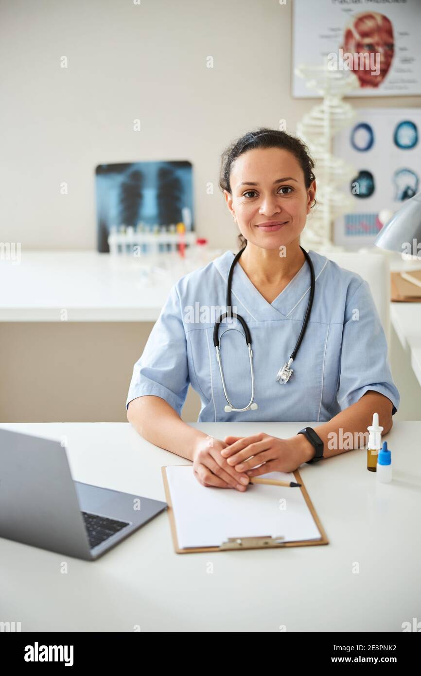 Collected physician folding her hands on a table Stock Photo - Alamy