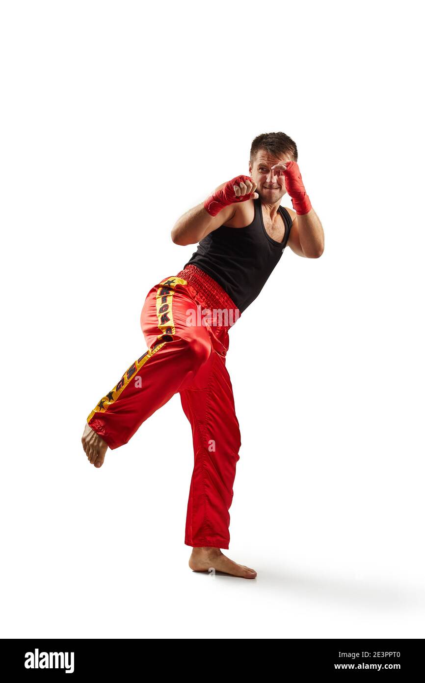 sporty man in red sports bandages on his hands making kick during ...