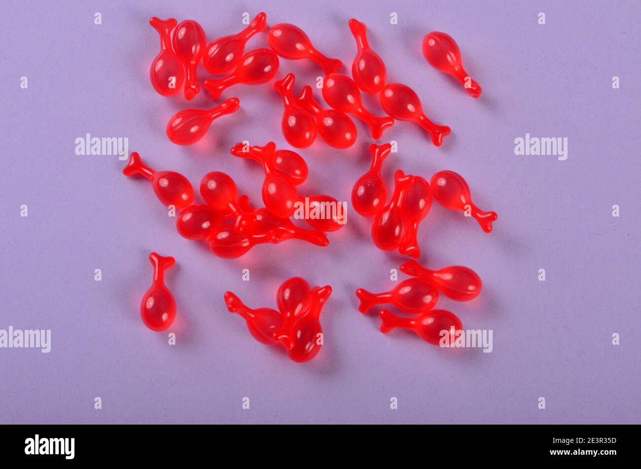 Pharmaceutical soft red gelatin capsules on violet background ...