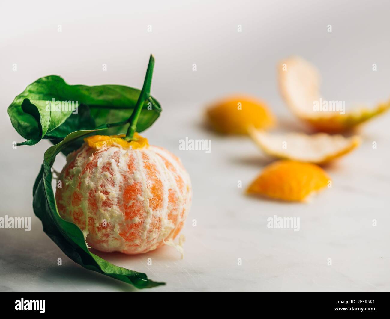 close up of tangerine with leaves. Tangerine peeled is on white table ...