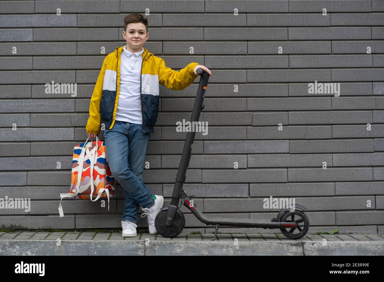 Teenager with backpack and electric scooter on brick wall background ...