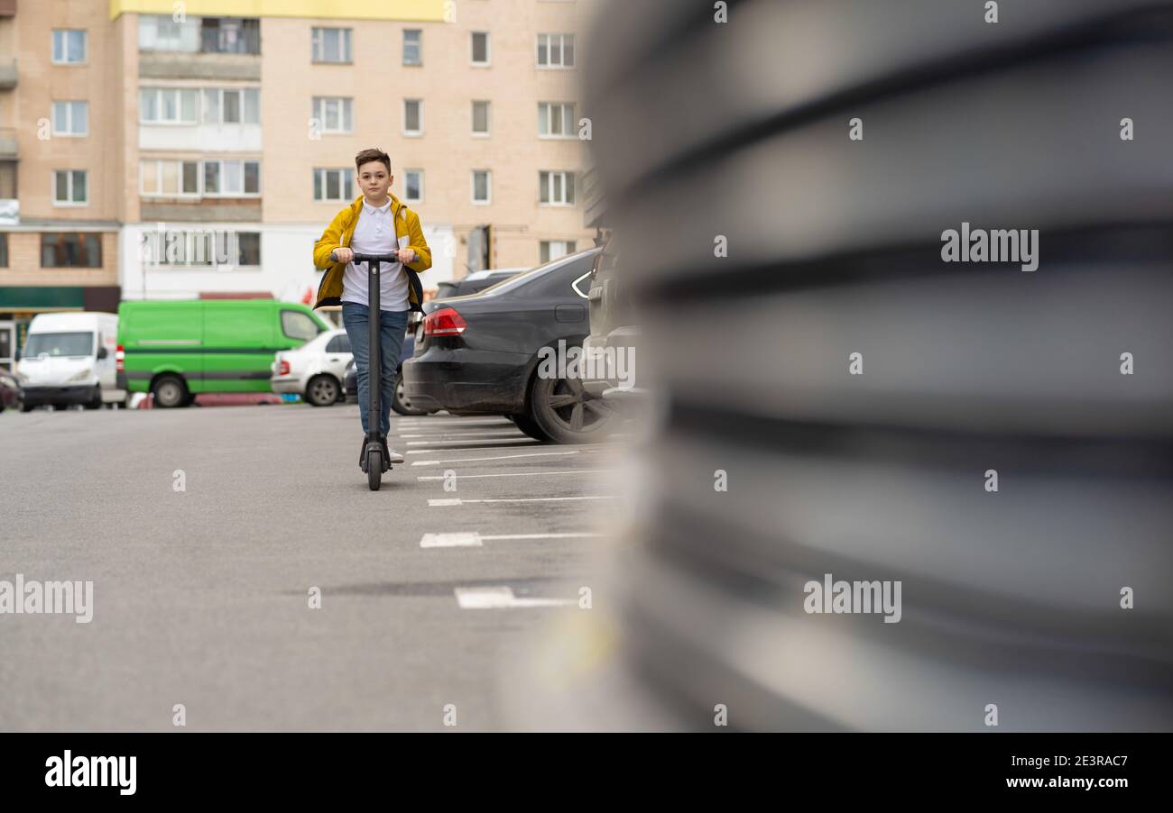 Teenager rides on electric scooter down street Stock Photo - Alamy