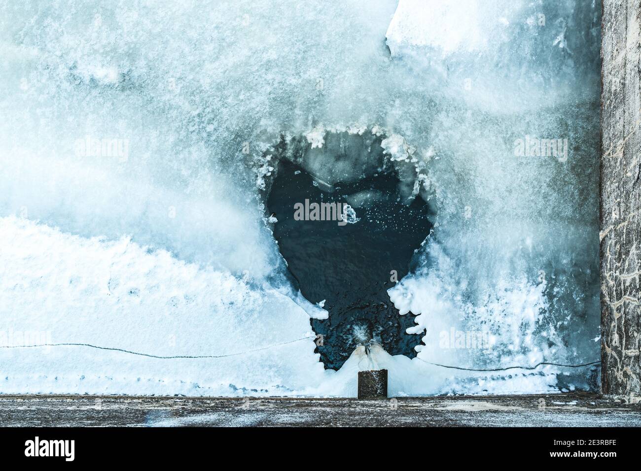 Rusty sewage pipe draining water into frozen river during winter Stock ...