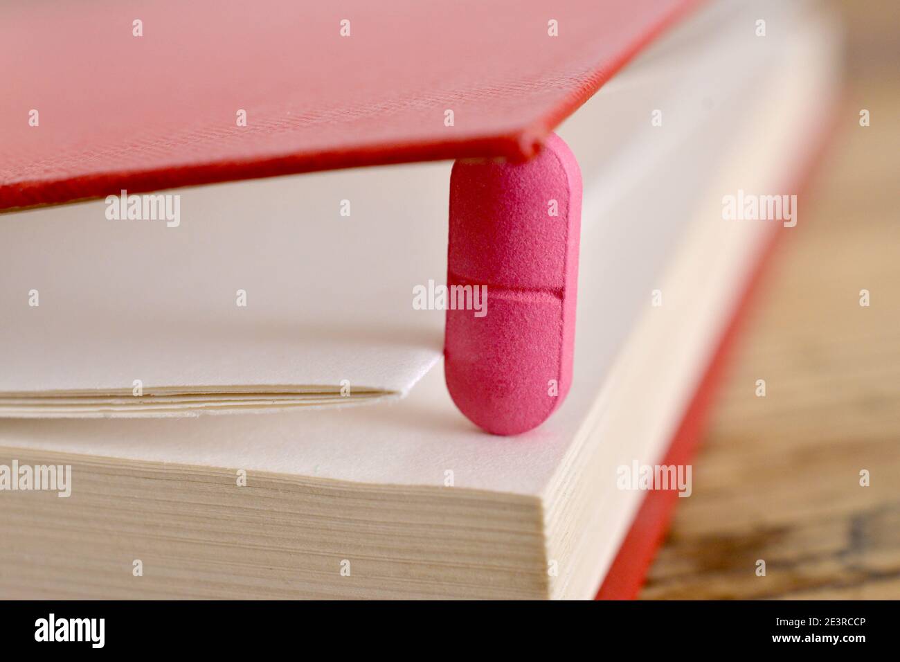 pink pill between book pages Stock Photo - Alamy