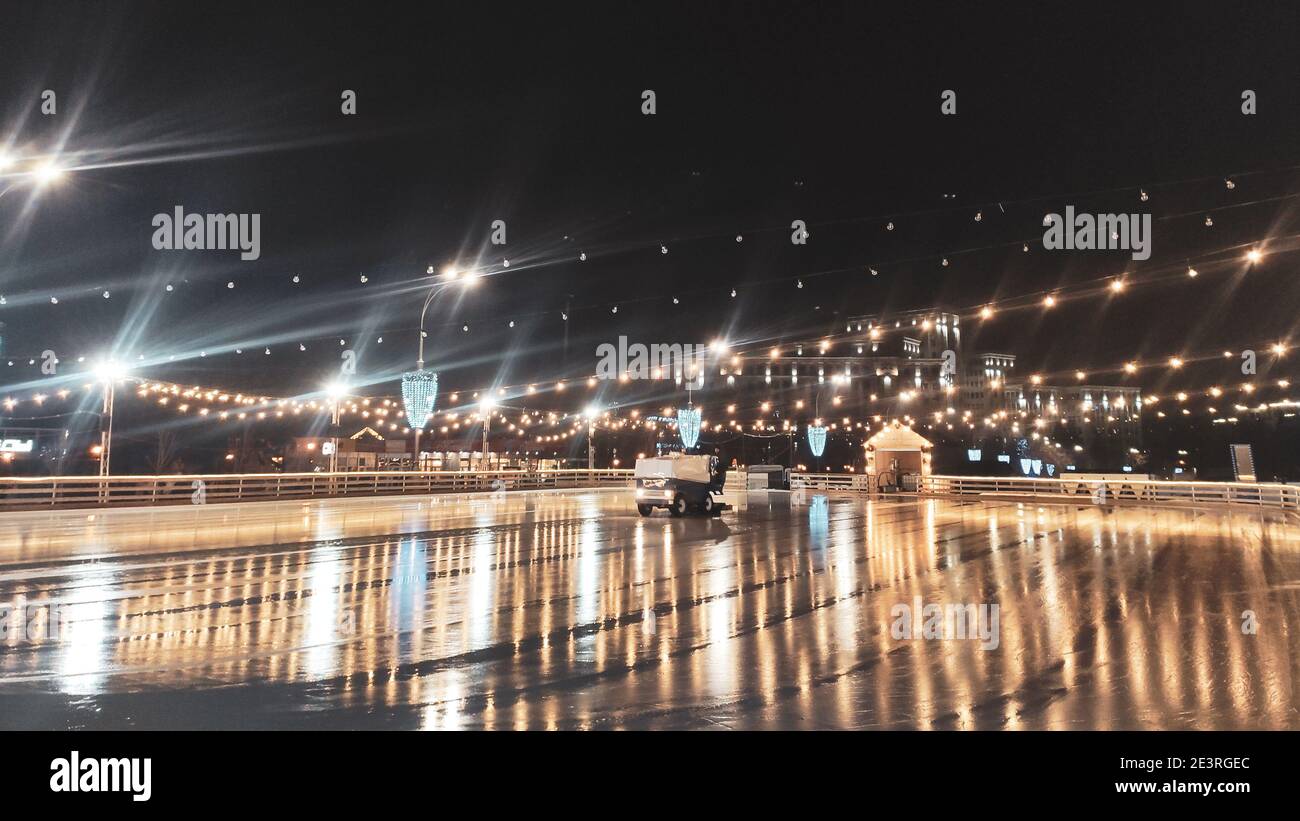 Winter night ice skating rink with cleaning machine on clear mirror ...