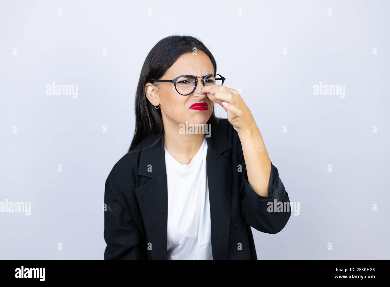 Beautiful business woman smelling something stinky and disgusting ...