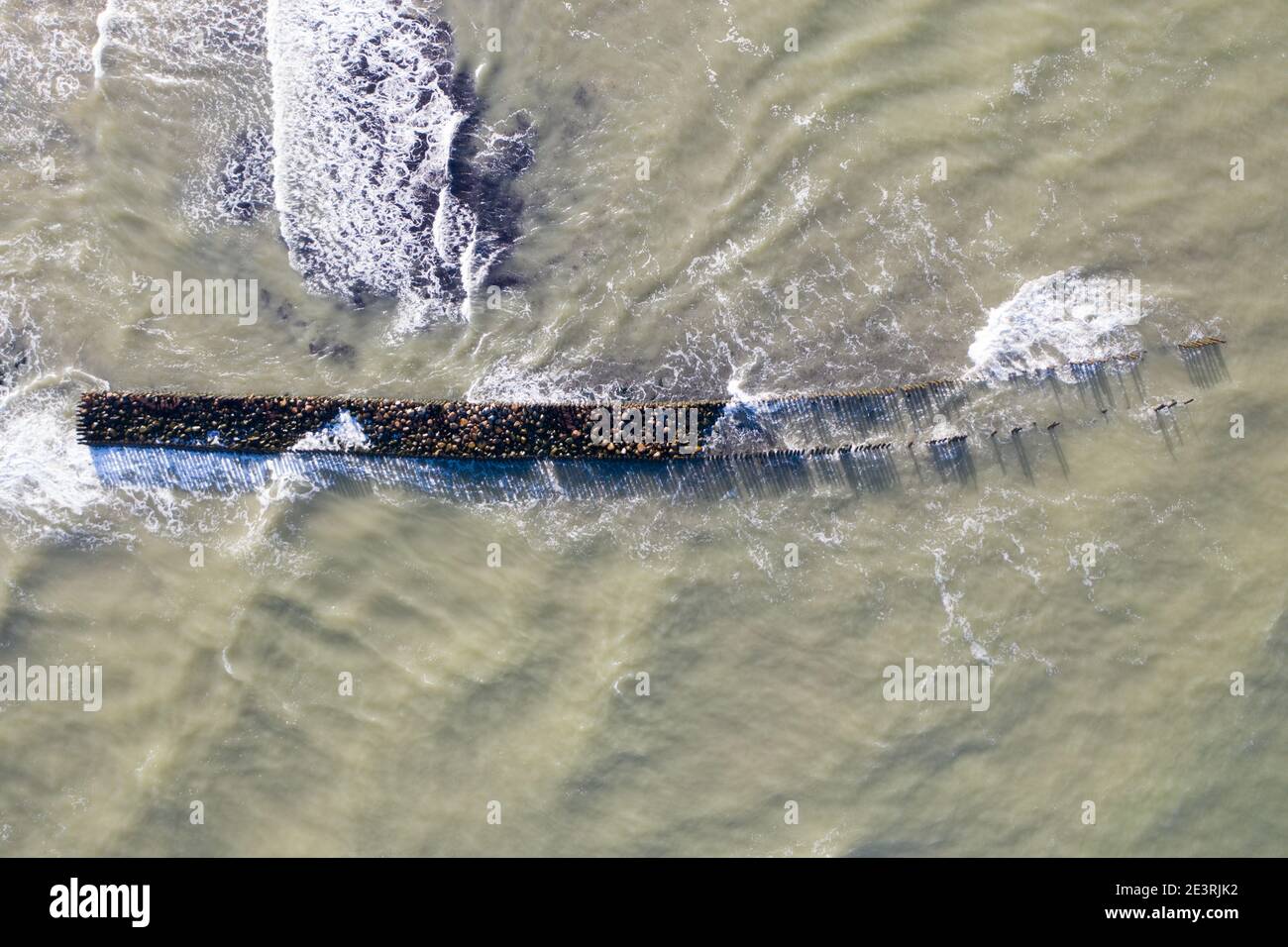 Aerial top down view of waves breaking against old stone breakwater ...