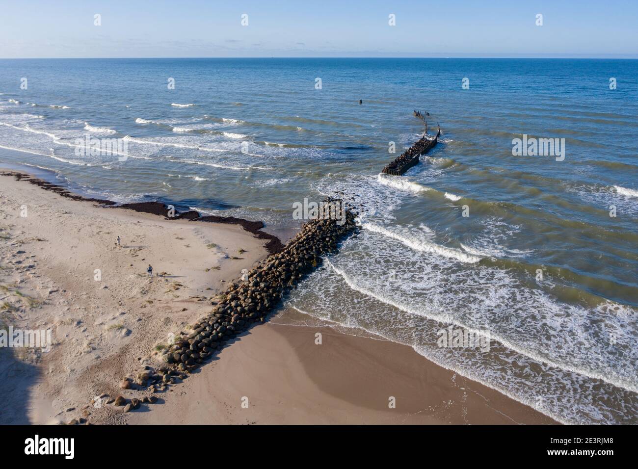 Aerial view of waves breaking against old damaged stone breakwater pier ...