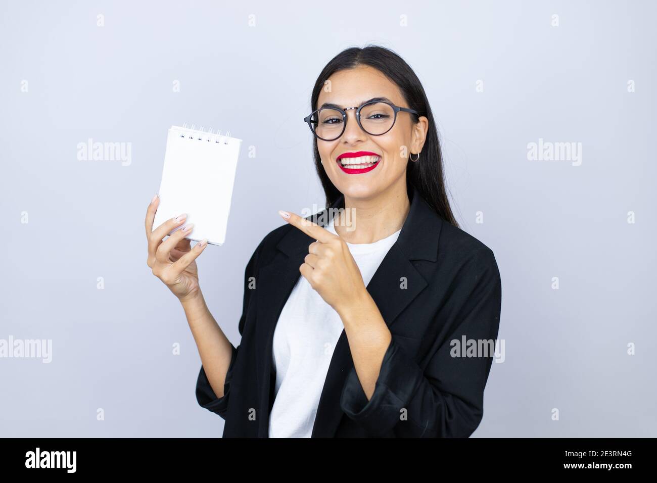 Beautiful business woman smiling showing and pointing a blank notebook ...